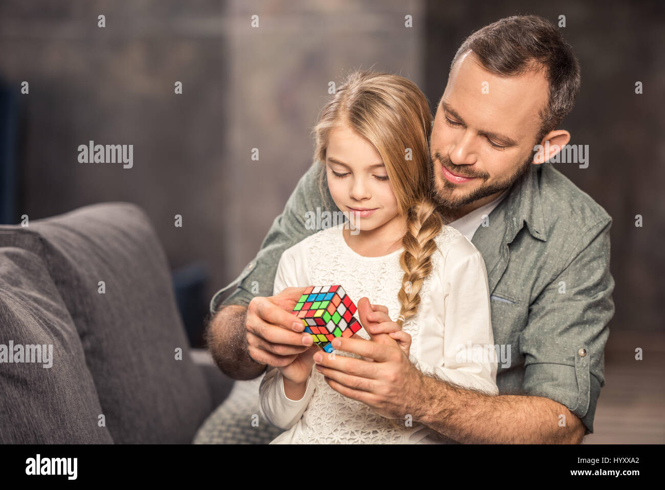 Pensive father and daughter playing with cube on couch Stock Photo - Alamy
