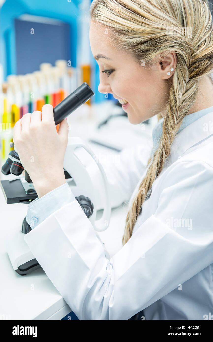 Young female scientist working with microscope in chemical laboratory ...