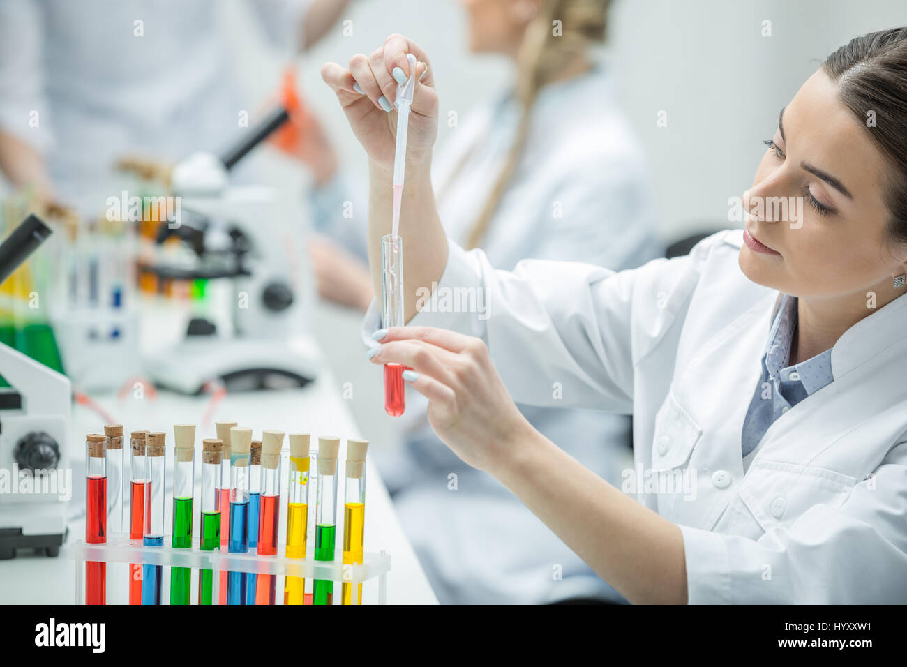 Female scientist in lab coat making experiment in chemical laboratory ...