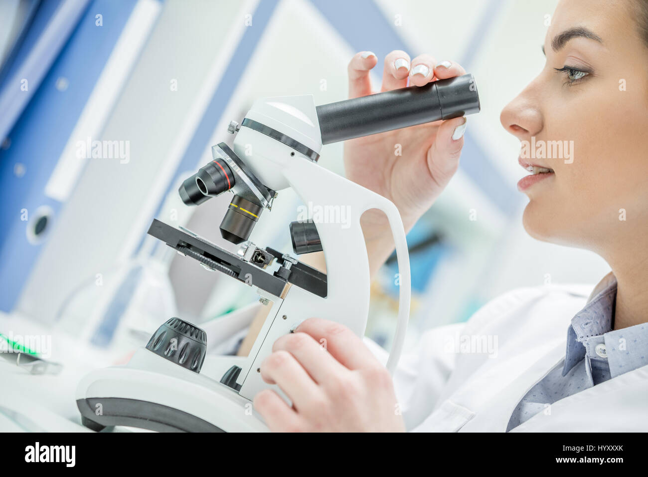 Profile of young female scientist working with microscope in laboratory ...