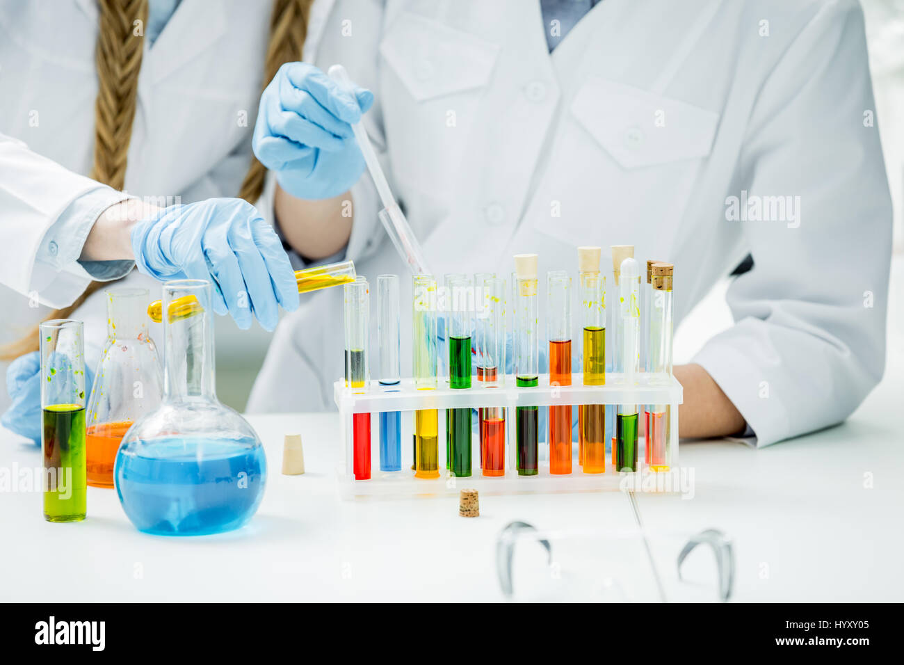 Mid section view of female scientists working with reagents in ...