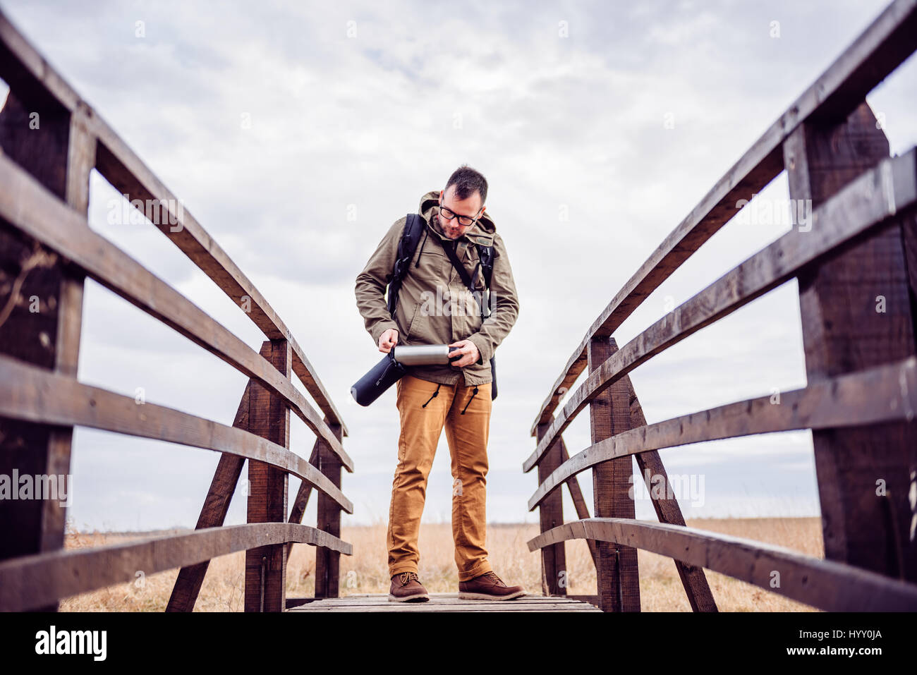 Hiker standing on a wooden bridge and pulling out water bottle Stock ...