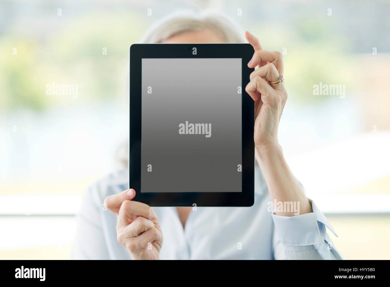 Woman holding digital tablet in front of her face Stock Photo - Alamy