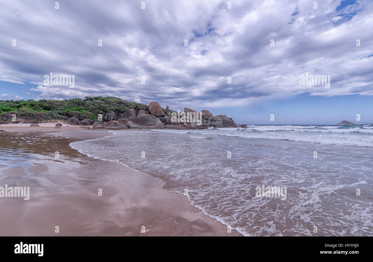 A low angle view of a sandy beach at low tide with the waves in the ...