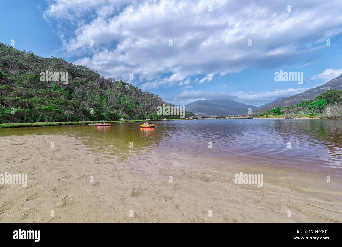 A low angle view of a river bank with inflatable boats floating on the ...