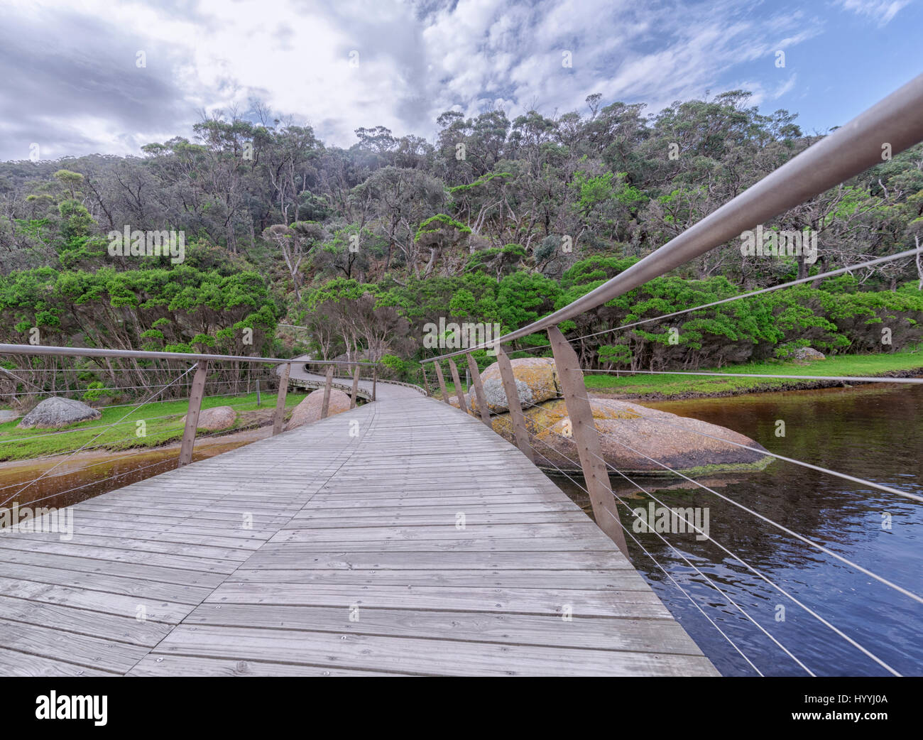 A low angle view of a wooden and iron bridge over a river leading to a ...