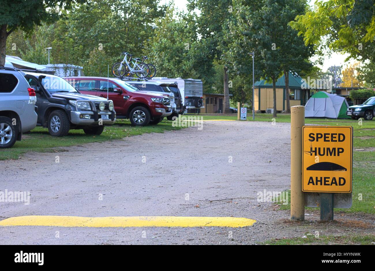 Speed hump sign at a campground road, with vehicles lined up on one ...