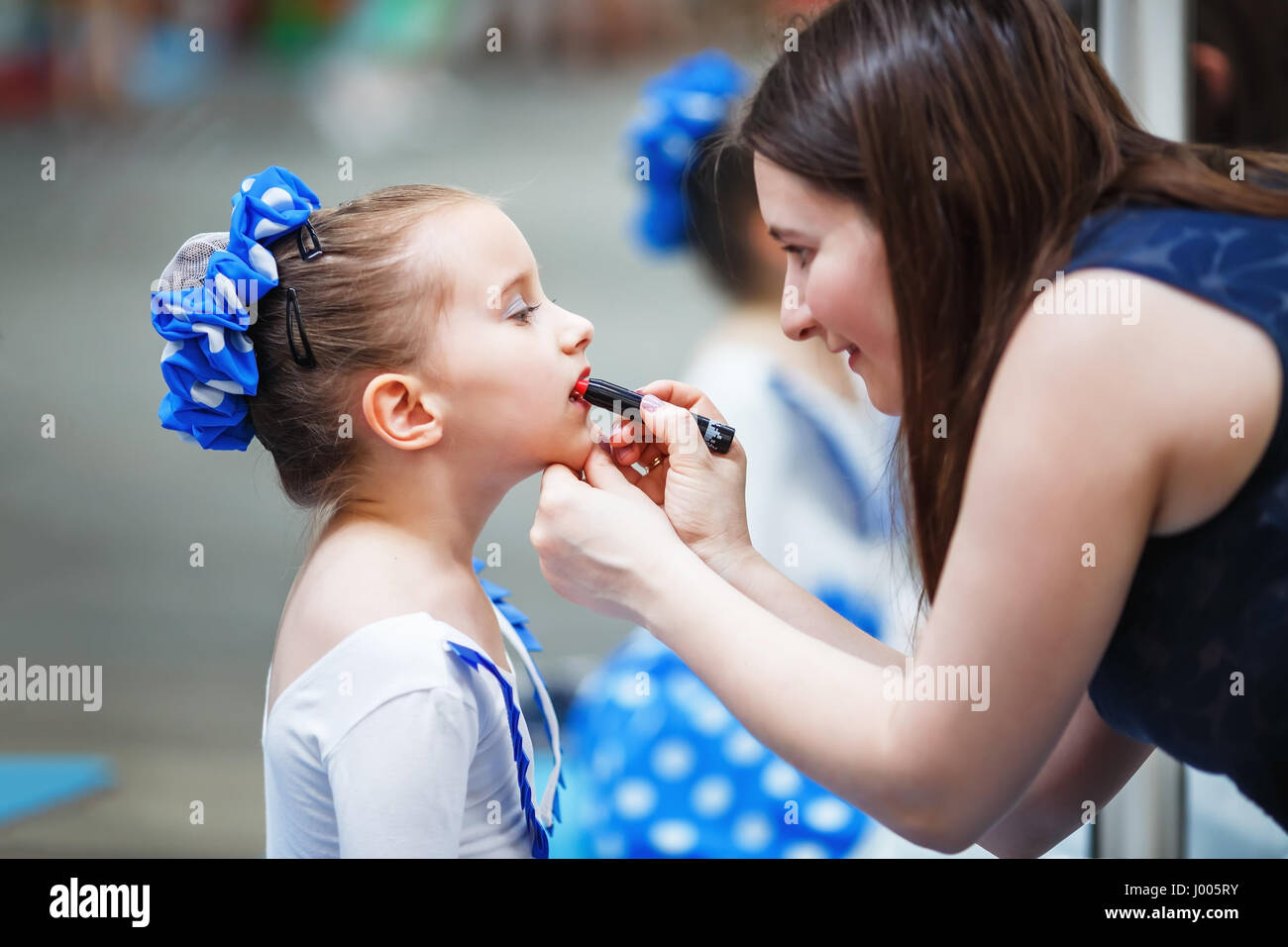 Mom paints lips with the lipstick of her little daughter before the ...