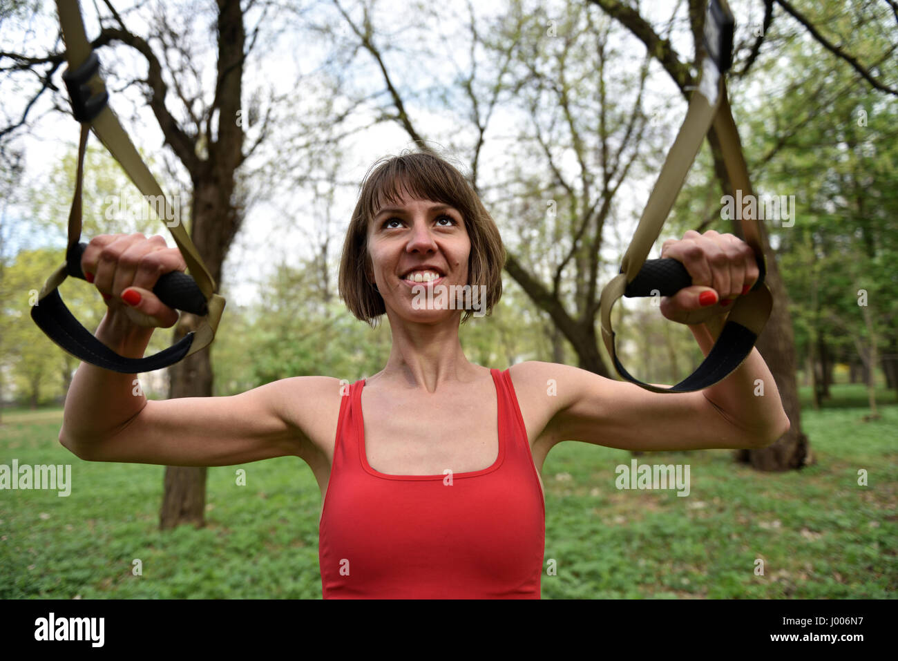 Woman doing arms biceps curl training with trx fitness straps in the ...