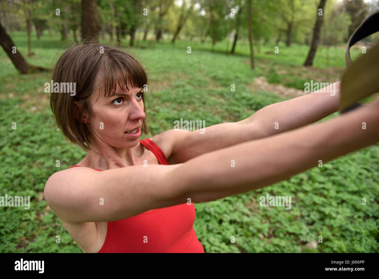 Woman doing arms biceps curl training with trx fitness straps in the ...