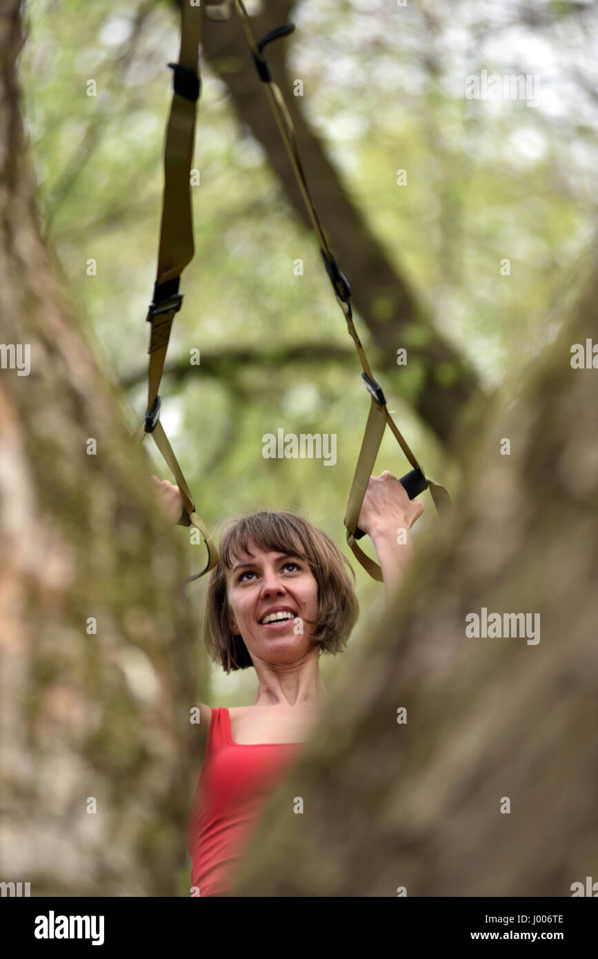 Woman doing arms biceps curl training with trx fitness straps in the ...