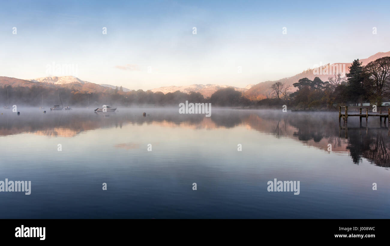 Mist rises from the calm waters of Windermere lake at Ambleside Pier ...