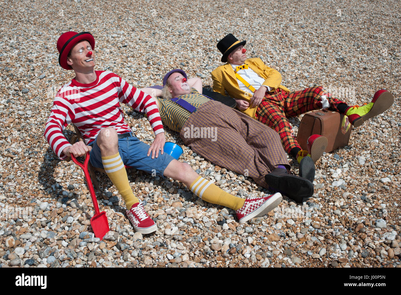 Three clowns sitting on the beach sunbathing on a sunny day during the ...