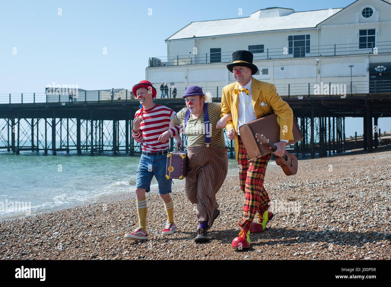 Three clowns walking along the beach having fun on a sunny day during ...