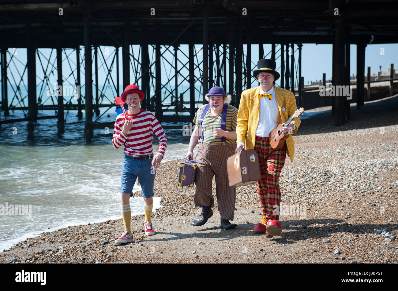 Three clowns walking along the beach having fun on a sunny day during ...