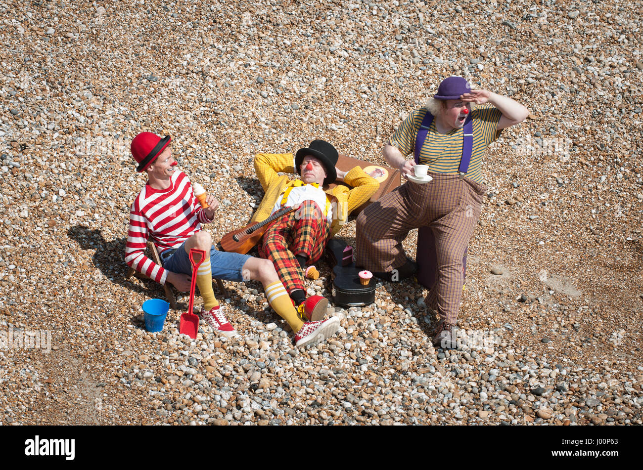 Three clowns sitting on the beach enjoying a picnic while drinking tea ...