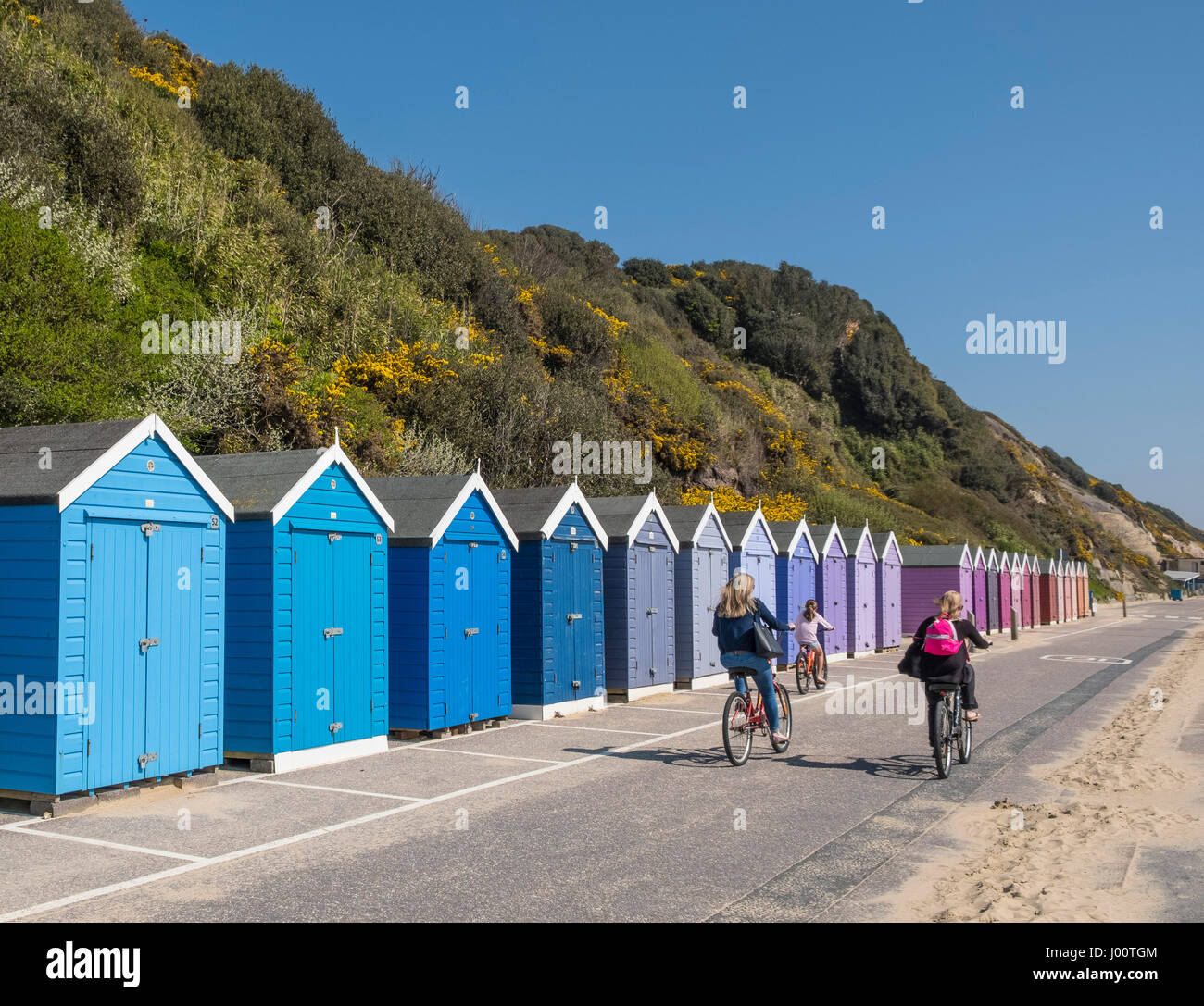 A line of colourful Beach Huts on Bournemouth Promenade with cyclists ...