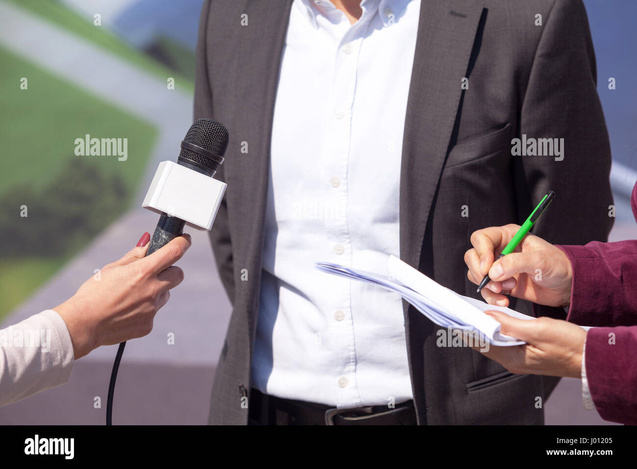 Reporters conducting press interview, holding microphone, writing notes ...