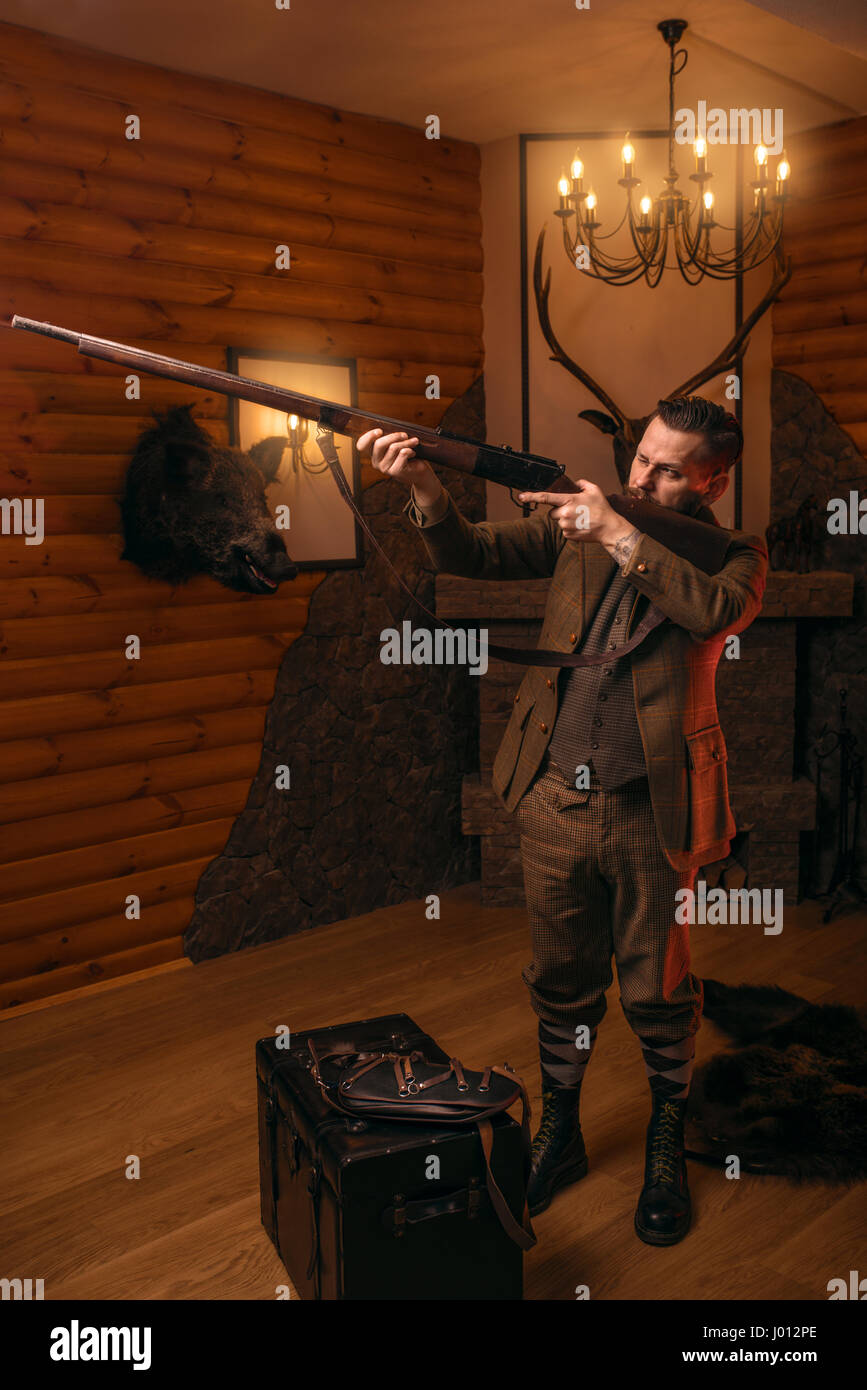 Hunter man aims of the antique hunting rifle. Fireplace, stuffed wild ...