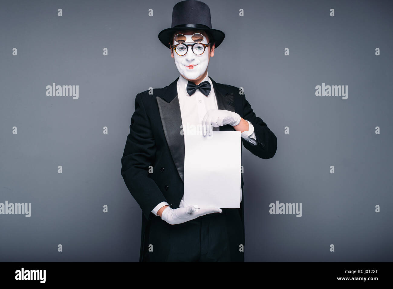 Male mime actor with empty paper sheet. Pantomime in suit, gloves ...