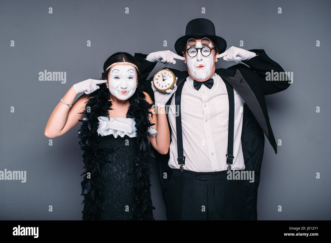 Pantomime actors performing with alarm clock. Comedy artist and actress ...