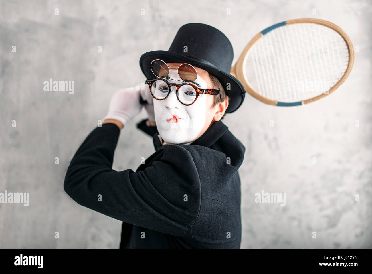 Pantomime actor performing with badminton racket. Comedy mime artist in ...