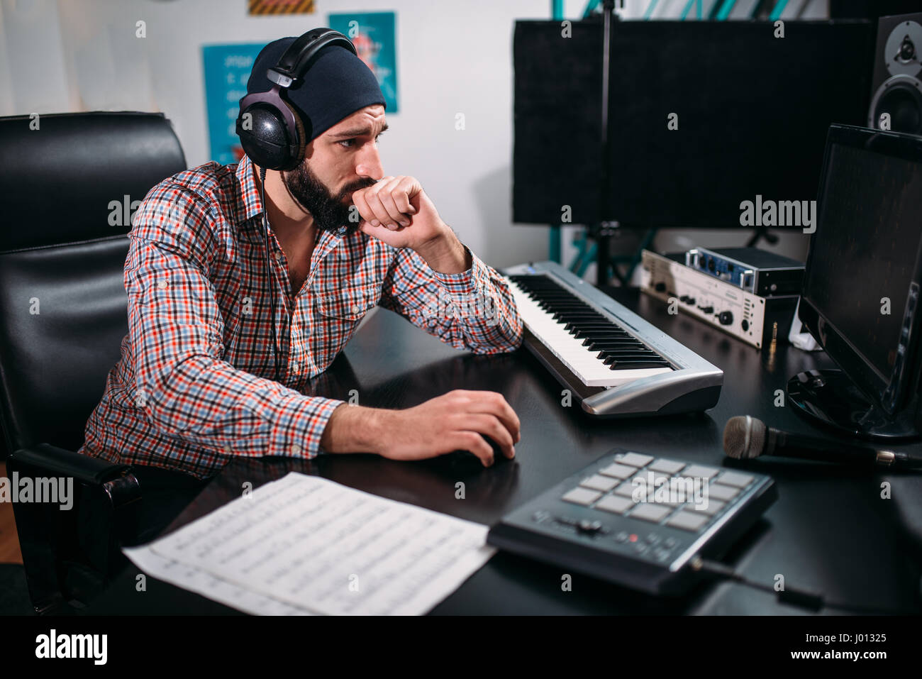 Audio engineer in headphones work with musical keyboard in studio ...