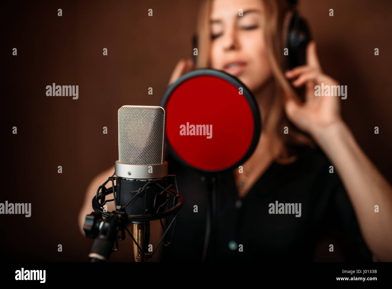 Female singer in headphones against microphone, song record in music ...
