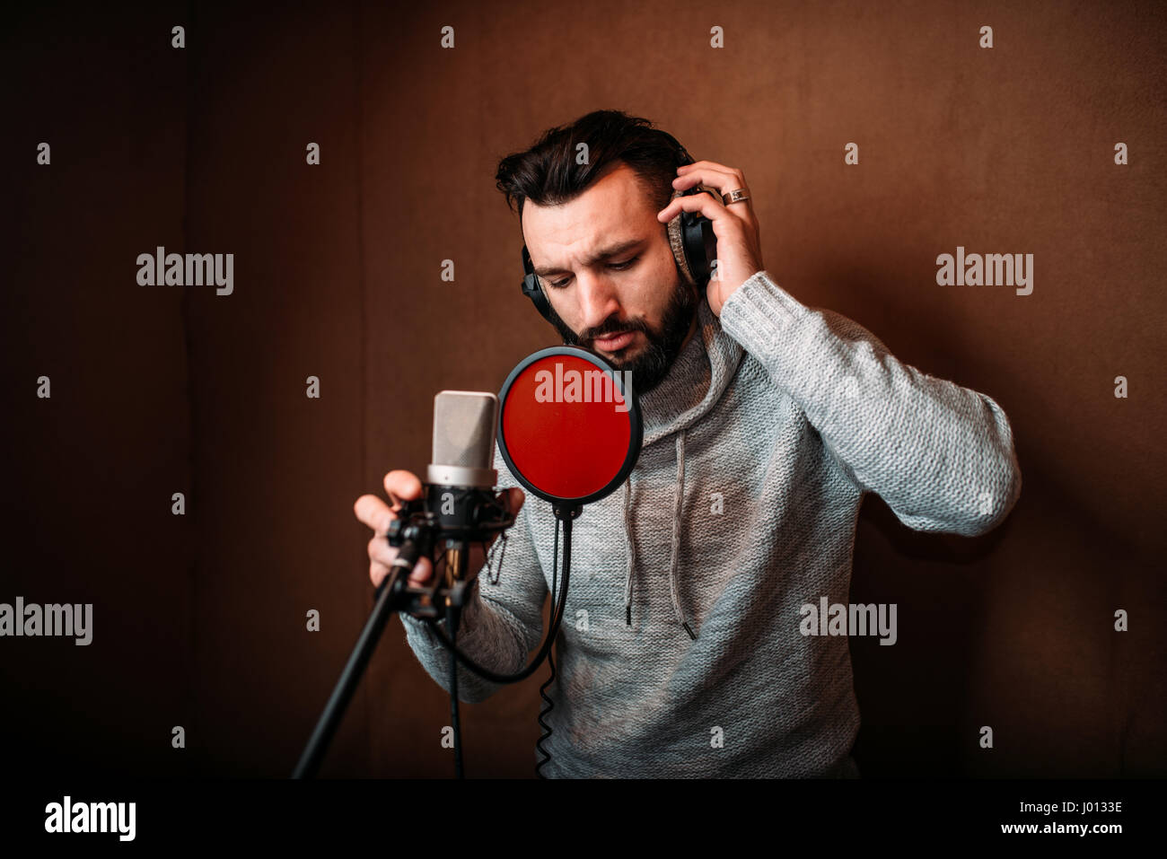 Male singer recording a song in music studio. Vocalist in headphones ...