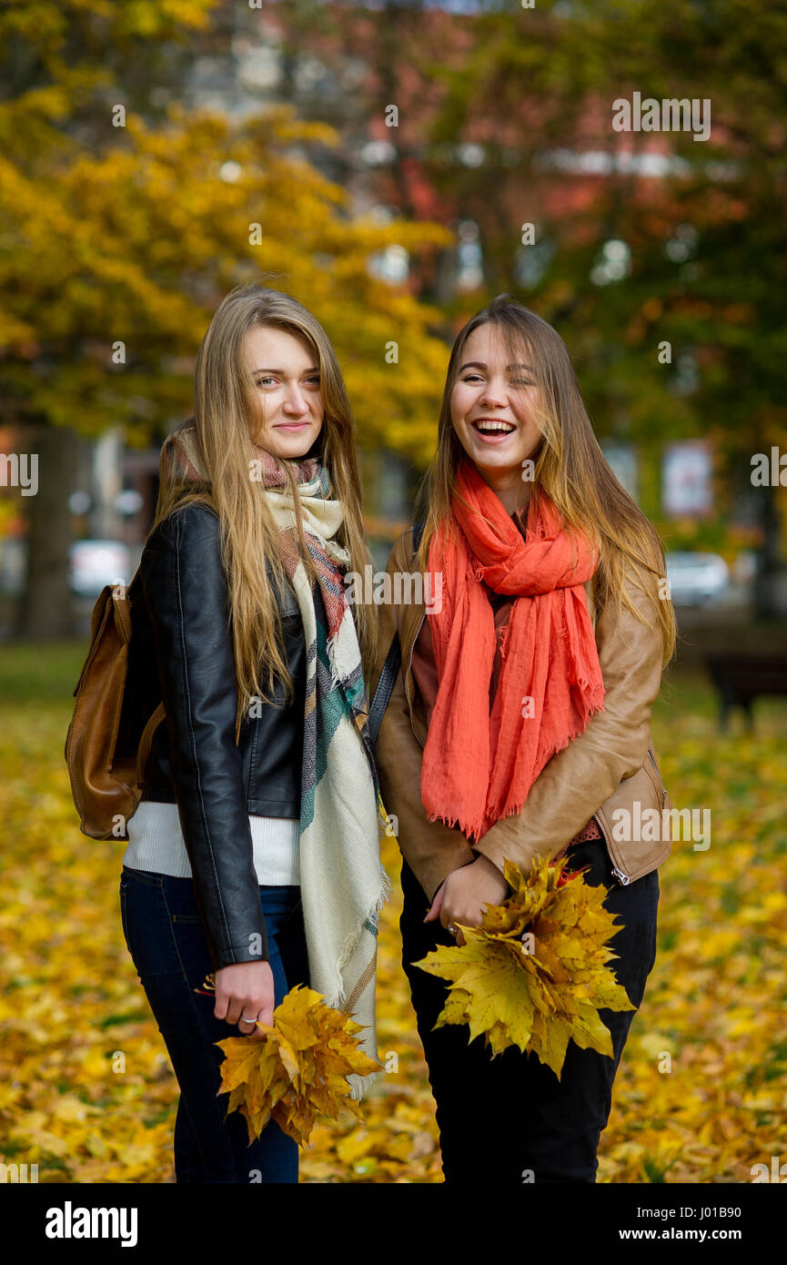 Two girls with bouquets of autumn leaves. Cute young students stand in ...