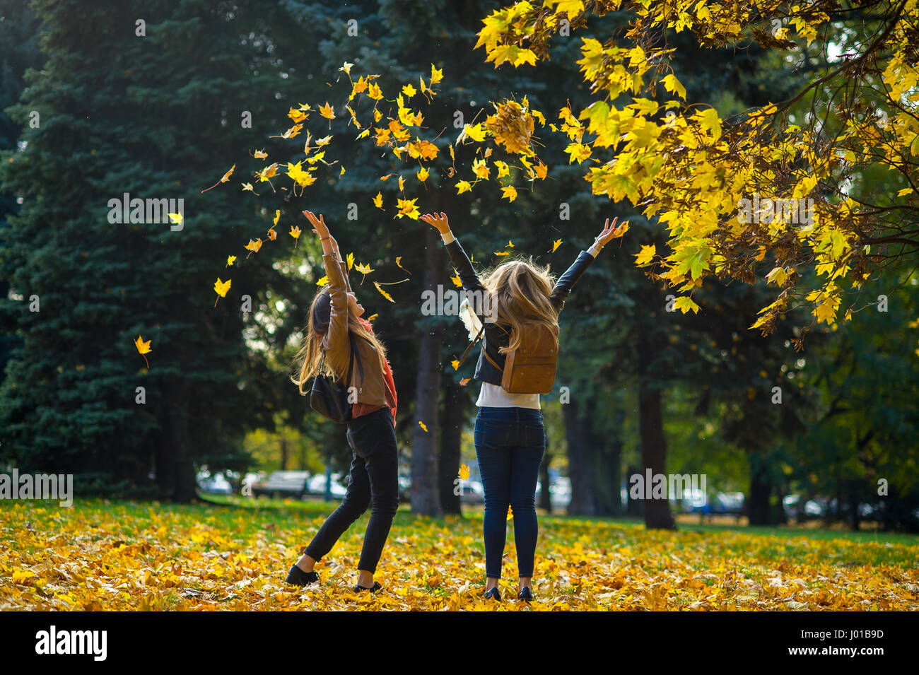 Mellow autumn. Two cheerful girls are students walk in the autumn park ...