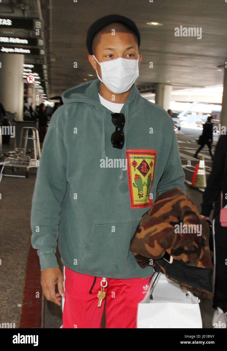 Pharrell Williams wears a surgical face mask as he arrives at Los ...