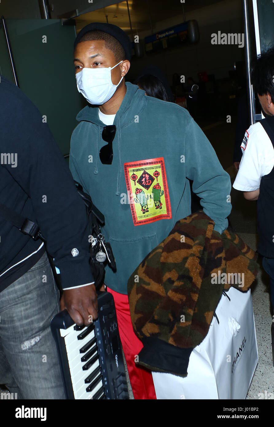 Pharrell Williams wears a surgical face mask as he arrives at Los ...