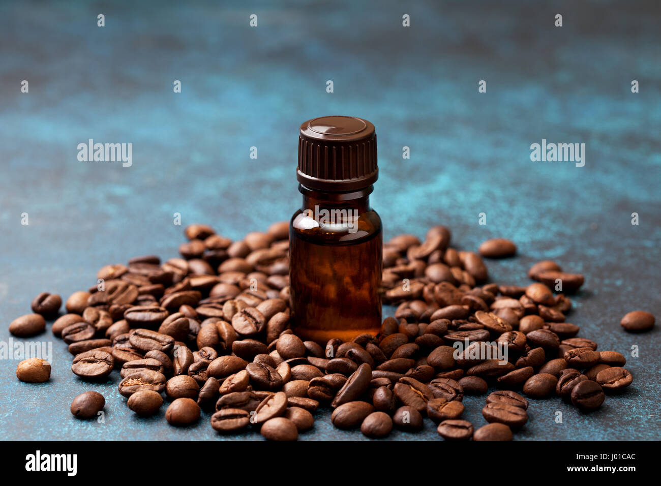 Coffee essential oil in a glass bottle, coffee beans on a blue ...