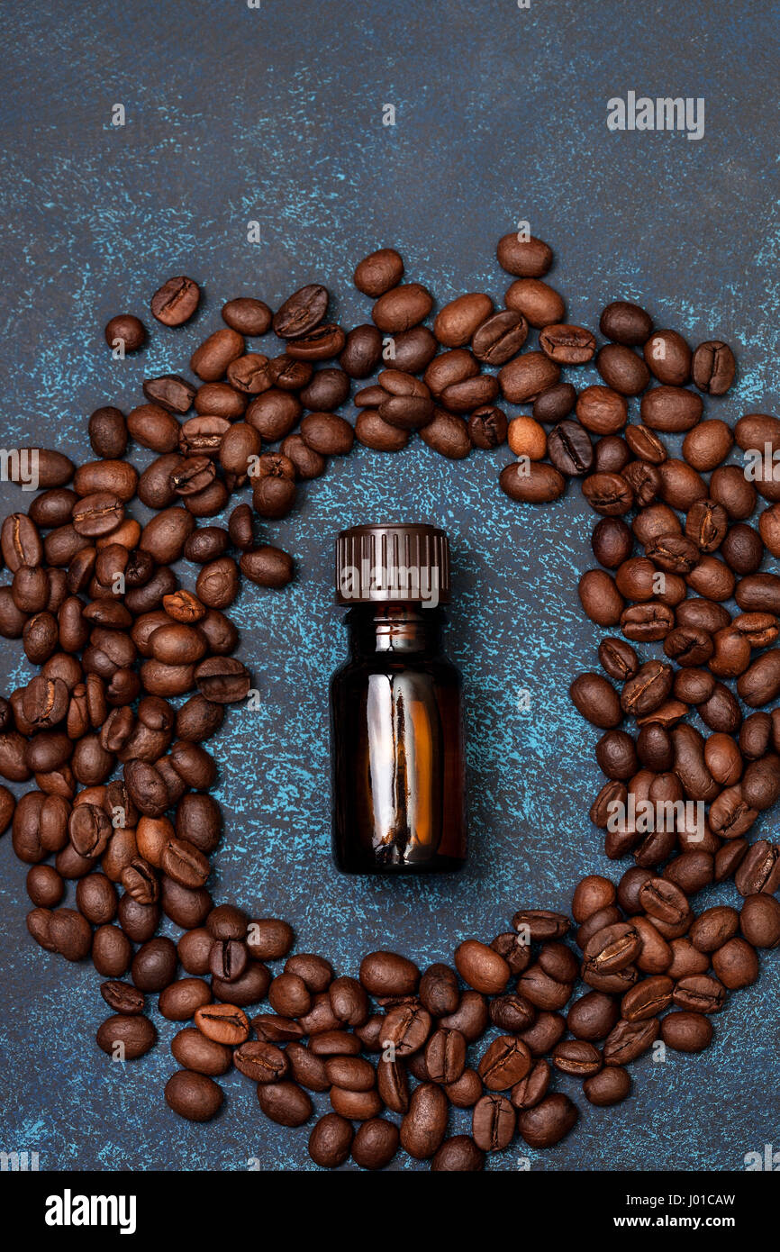 Coffee essential oil in a glass bottle, coffee beans on a blue ...