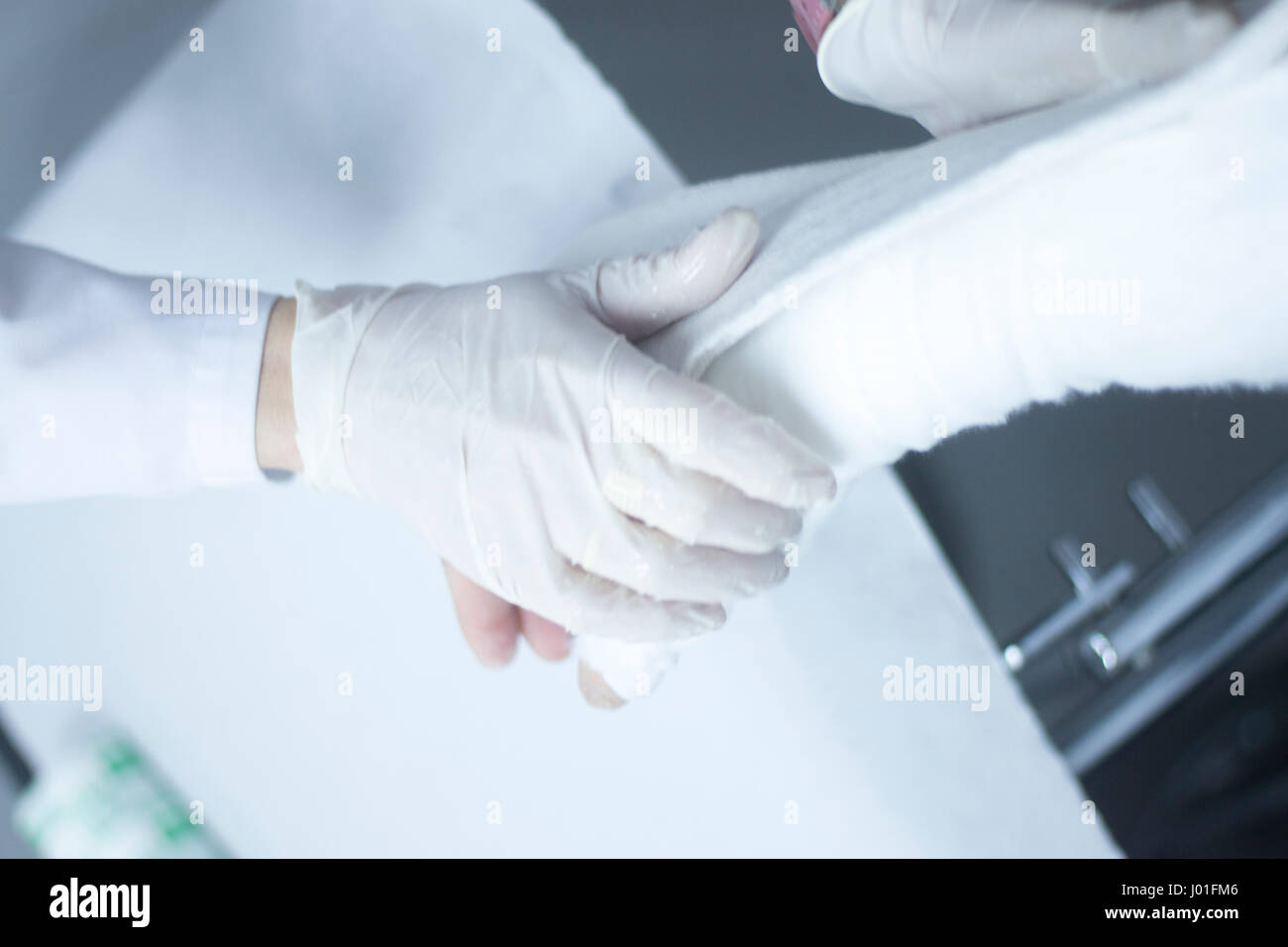Doctor applying a plaster cast and bandages to patient forearm and ...