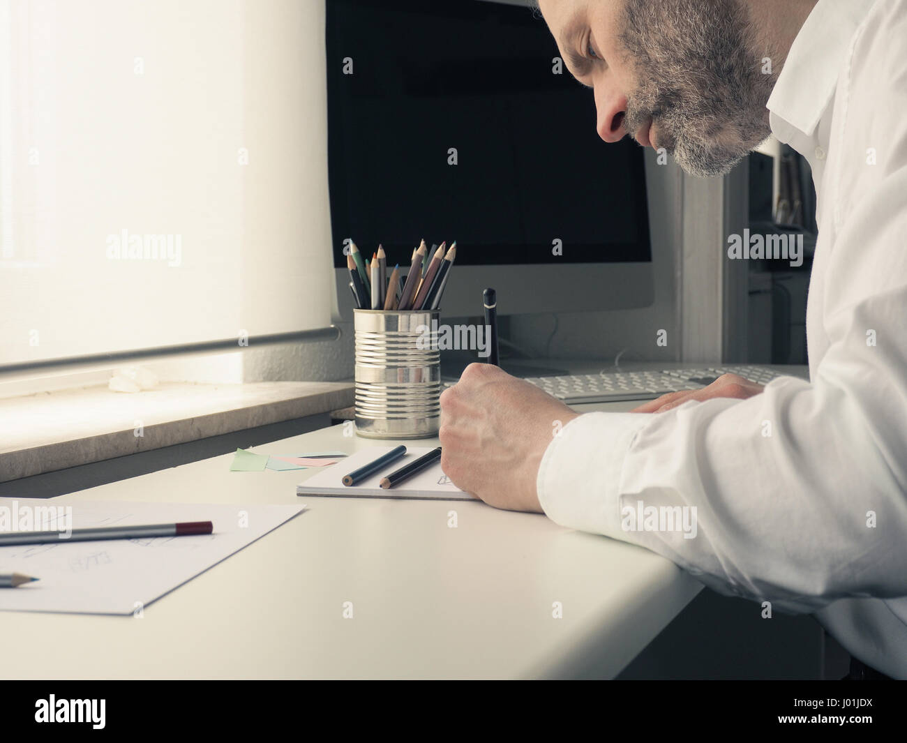 Man is drawing on a paper sheet, creativity concept with natural light ...