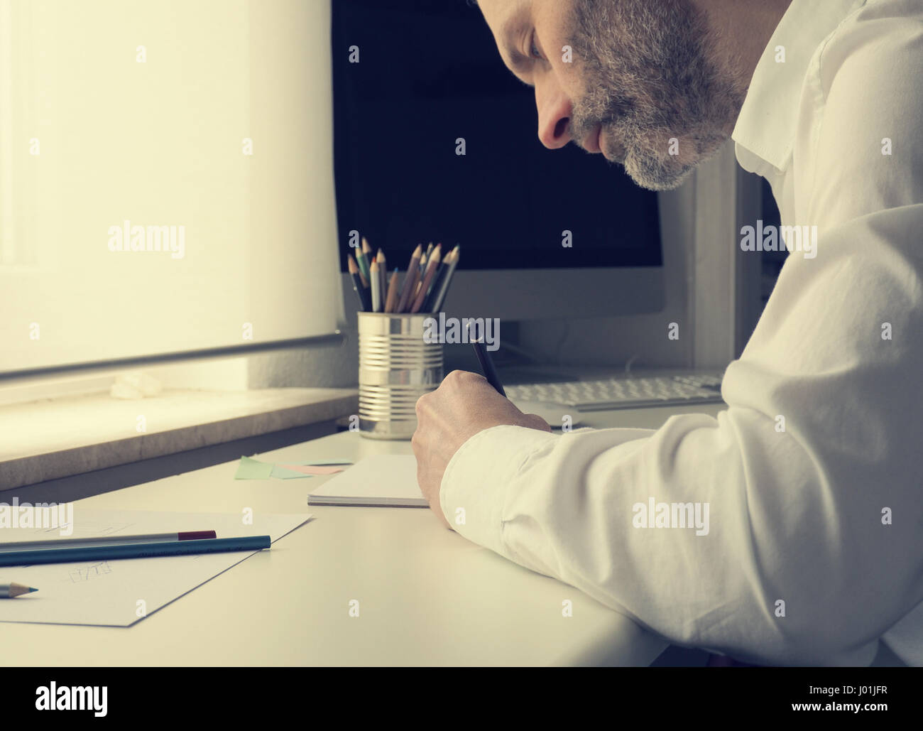 Man is drawing on a paper sheet, creativity concept with natural light ...