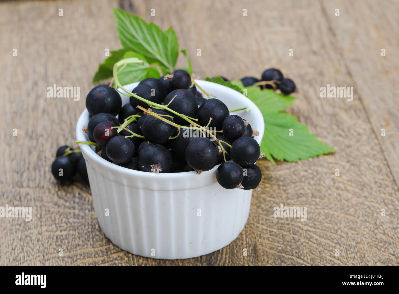 Black currants heap with leaves on wood background Stock Photo - Alamy