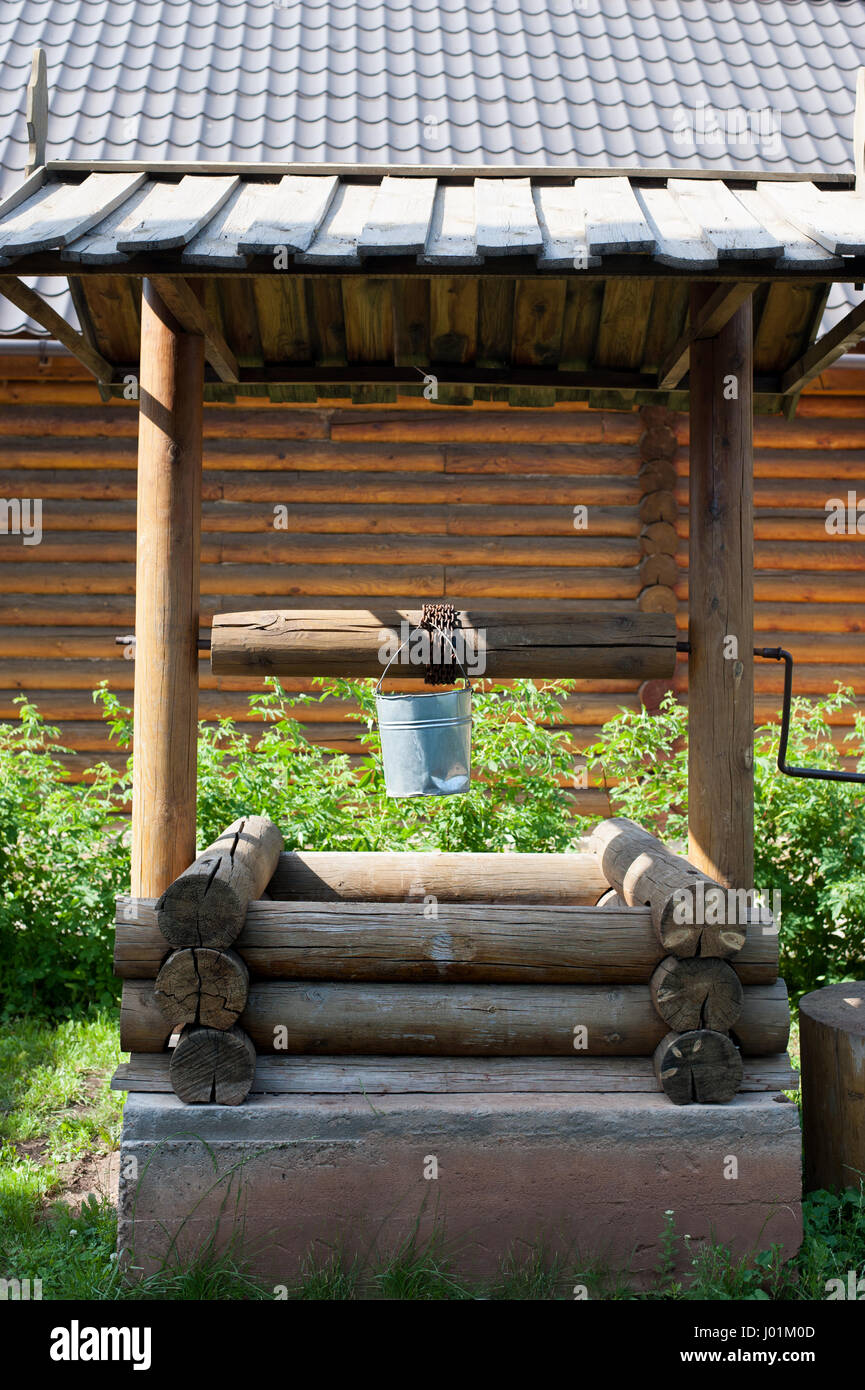 Tradition wooden village well with bucket Stock Photo - Alamy