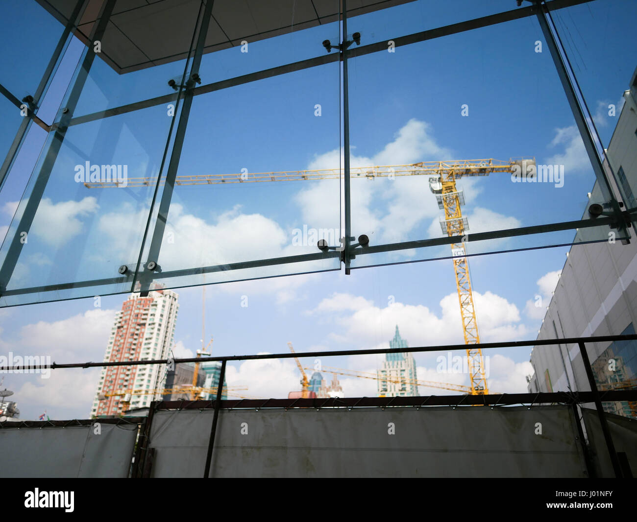 Construction crane through glass window with background of blue sky ...