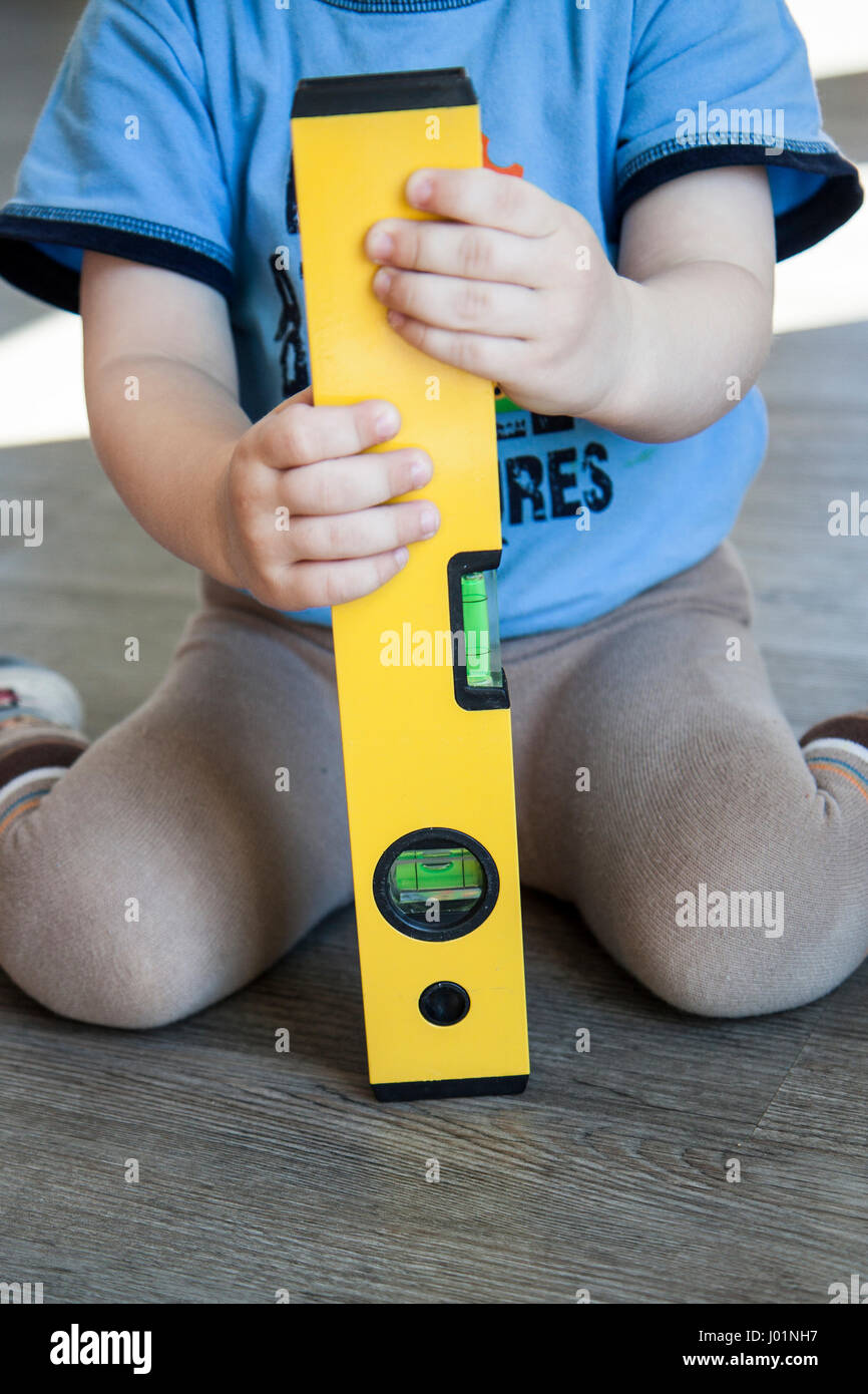 spirit level in young boy hand - child with waterlevel, wood floor ...