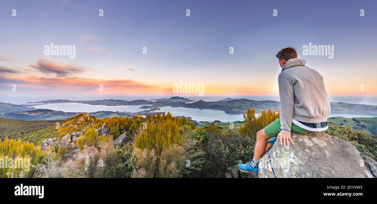Man sitting on rocks, view from Mount Cargill Dunedin with Otago Harbor ...