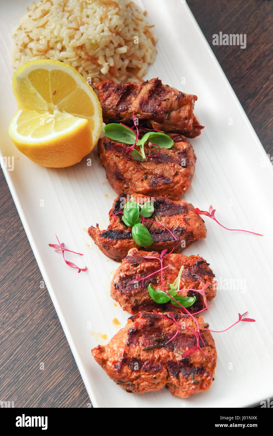 grilled meat dish of lamb pieces with garnish Stock Photo - Alamy