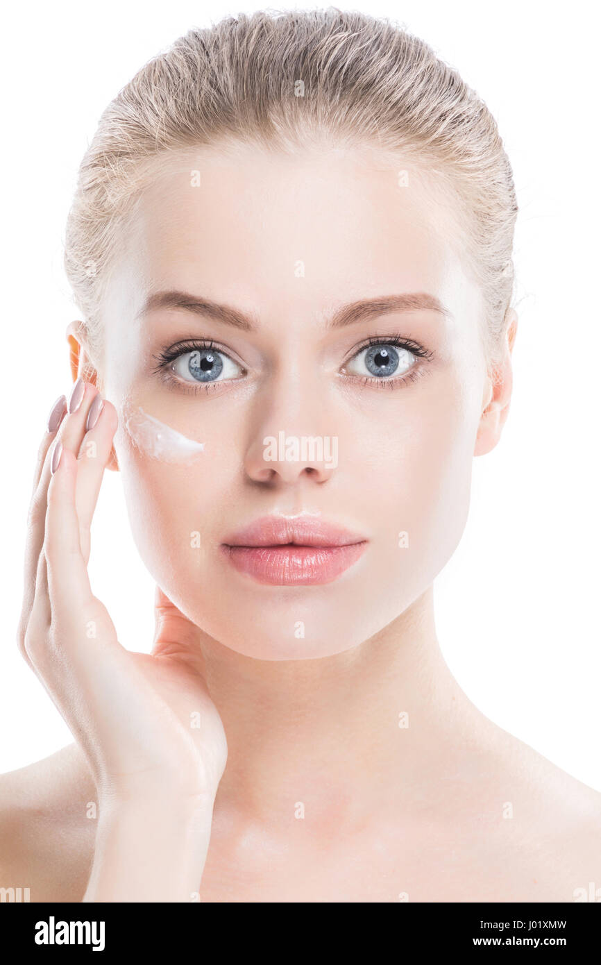 Beautiful young woman with cream on clean fresh face skin close up ...