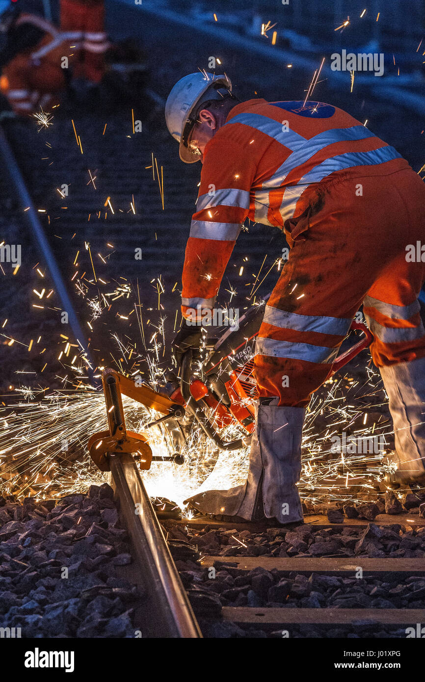 Rail workers cutting and laying new tracks on night shift Stock Photo ...