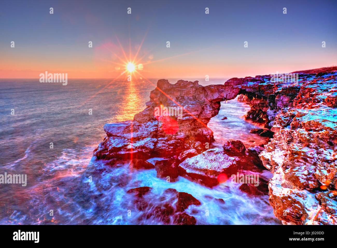 Beautiful sunrise over the sea and stone arch Stock Photo - Alamy