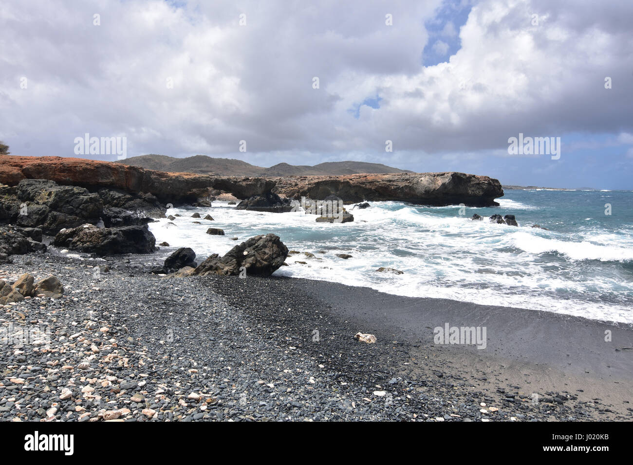 Dark lava rocks on the edges of the black sandstone beach in Aruba ...