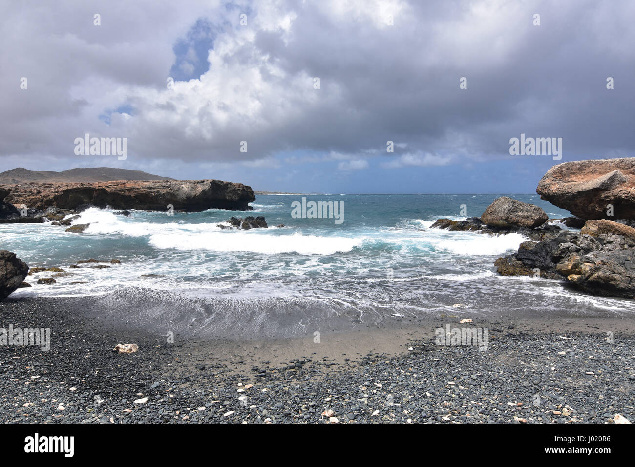 Waves receding on the black sand stone beach in Aruba Stock Photo - Alamy