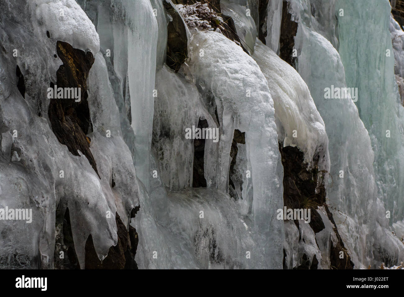 Multiple colour hues in ice fall frozen in flow down hillside with ...